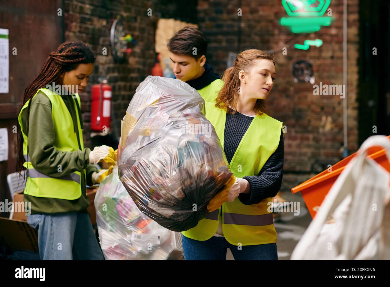 Young volunteers in gloves and safety vests sort through a pile of ...