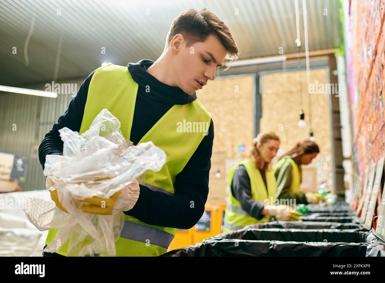 Young volunteer in yellow vest sorts trash into bin with eco-conscious ...