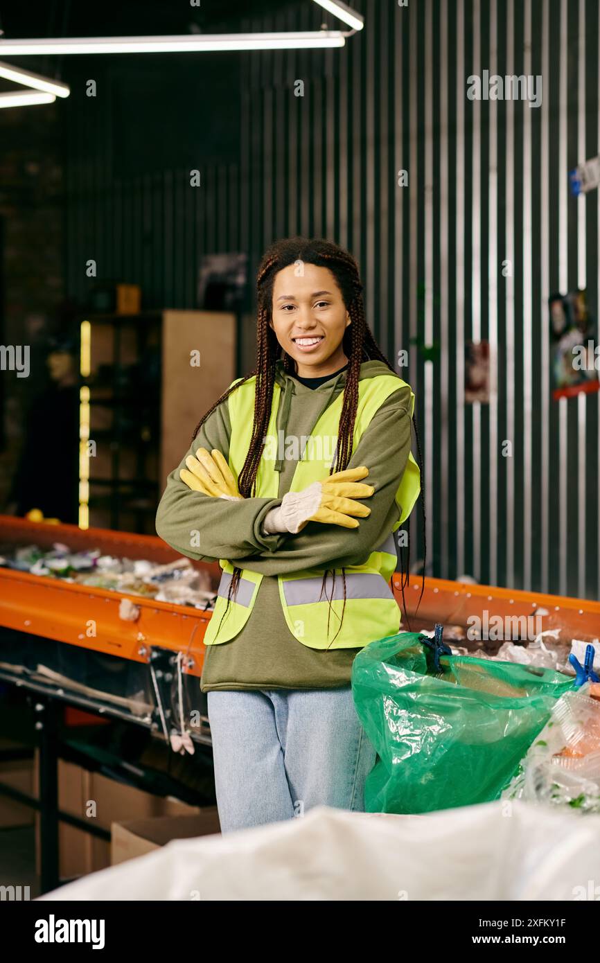 Young volunteer in gloves and safety vest stands with crossed arms ...