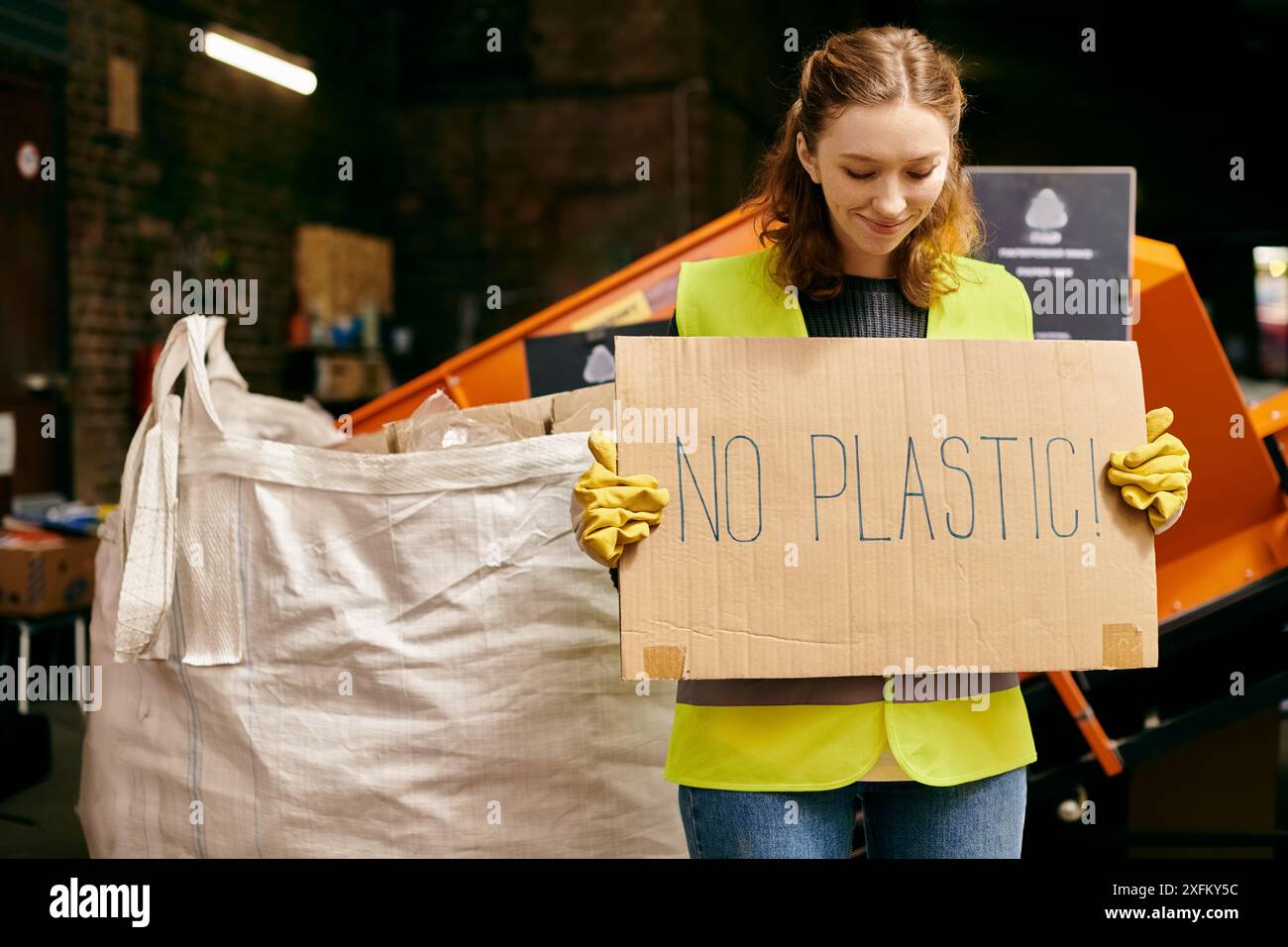 A young volunteer in gloves and safety vest holding a sign that reads ...