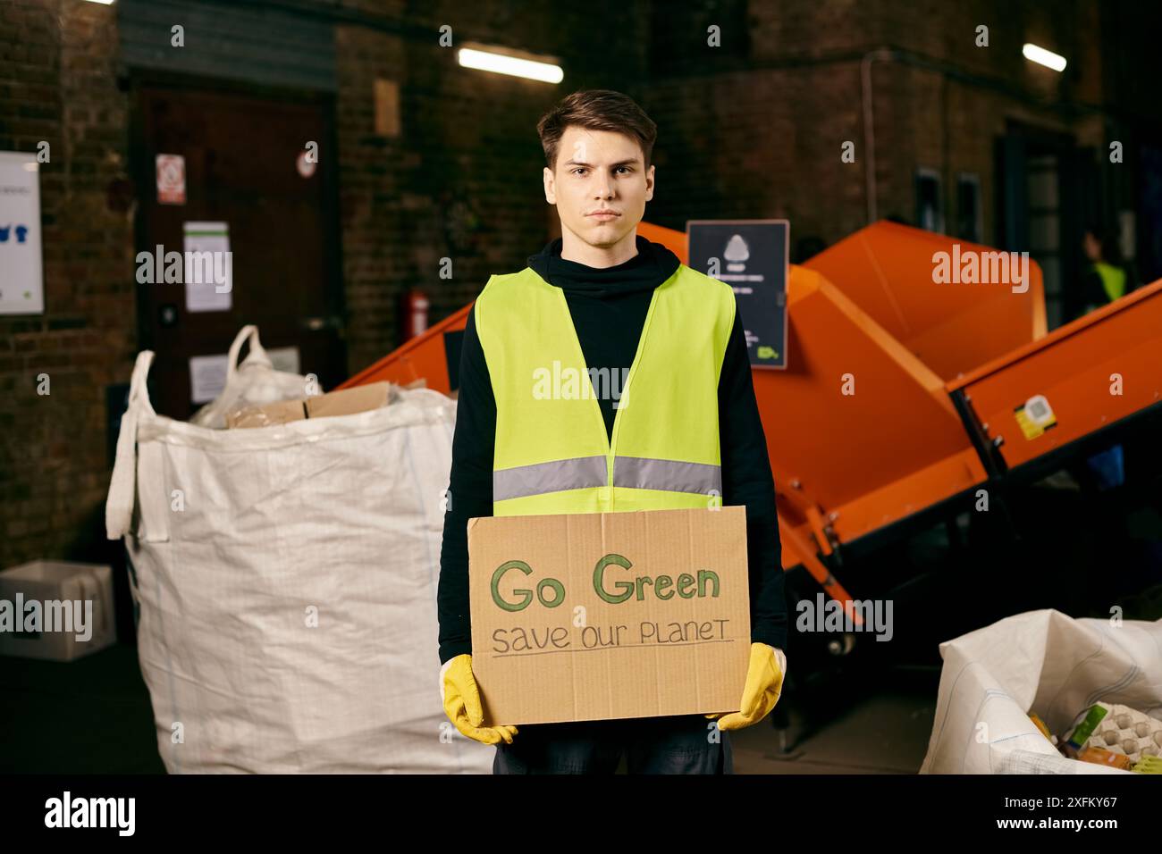 A young man holds a cardboard sign that says Go Green while wearing ...