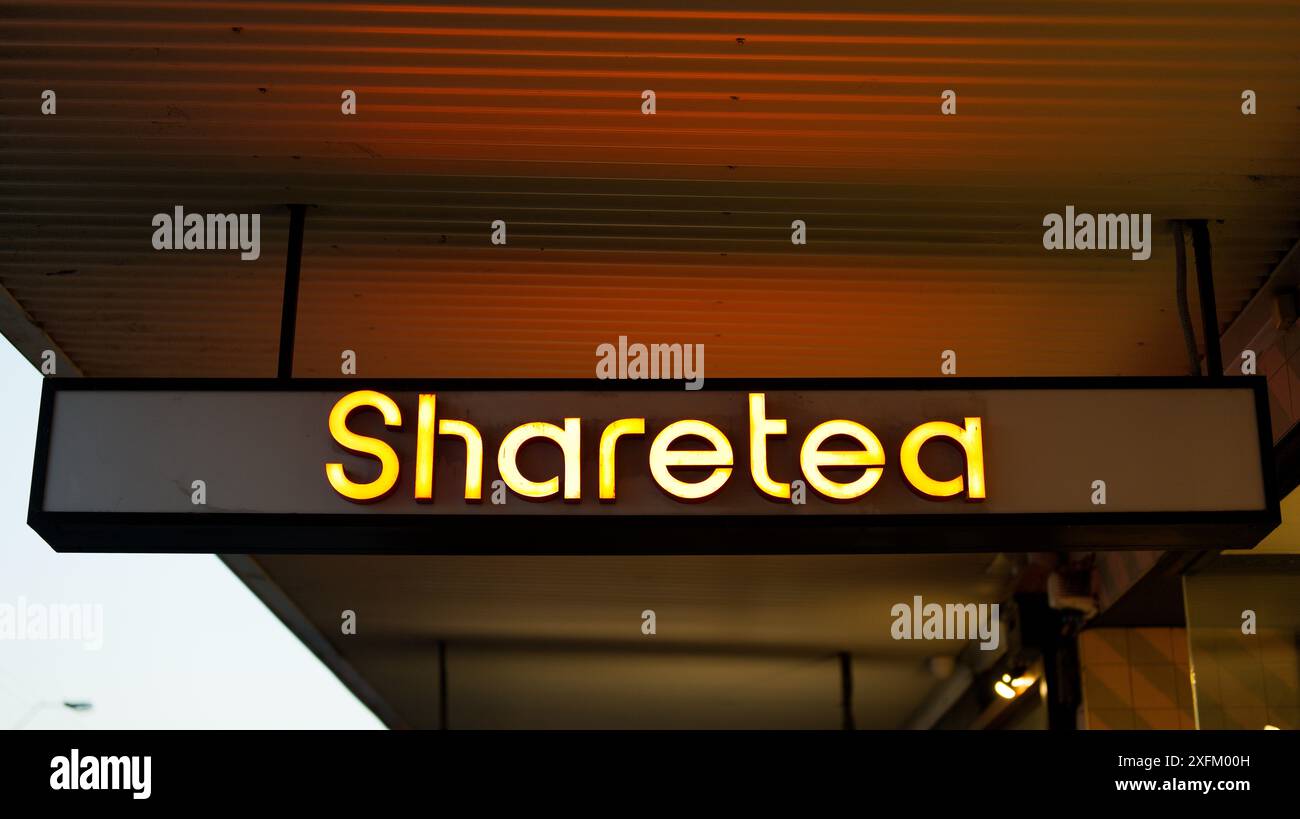 Illuminated Sharetea sign, giving off an orange glow, above the ...