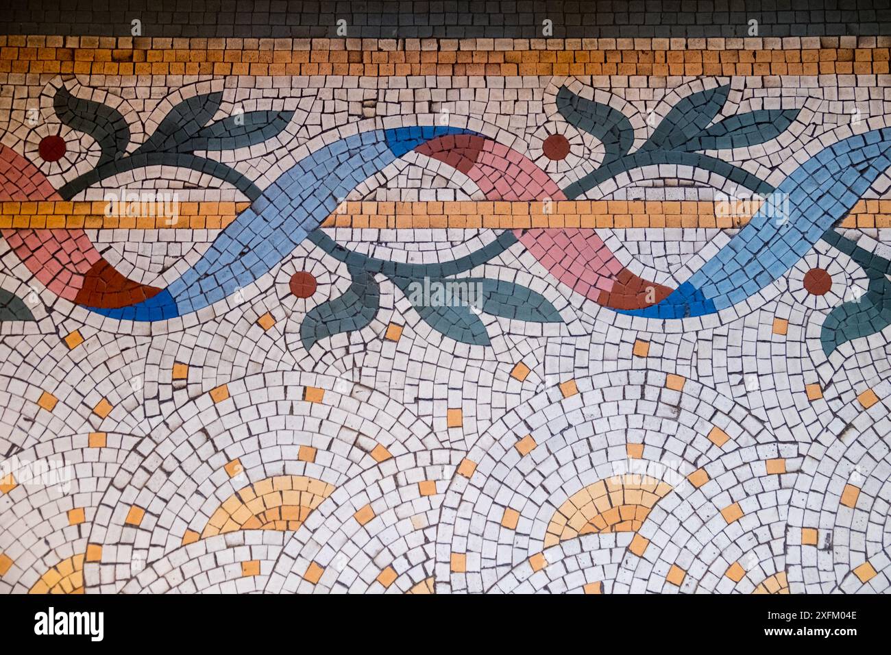 A mosaic tile floor with a blue and pink design. The tiles are arranged ...