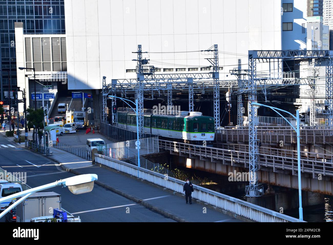 A green train on the Keihan line emerging from under the Keihan City ...
