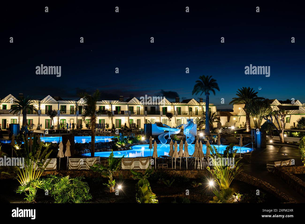 The pool area is lit up at night, creating a warm and inviting ...