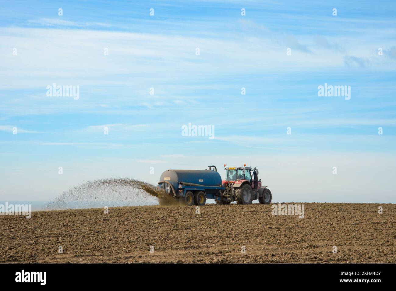 Tractor pulling tank spreading slurry over arable field, Dover, Kent ...