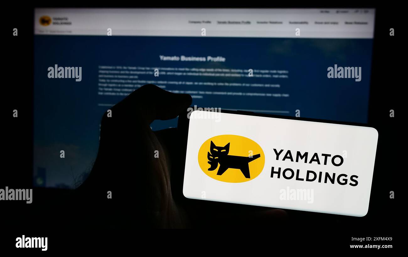 Person holding smartphone with logo of Japanese transport company Yamato Holdings Co. Ltd. in ...