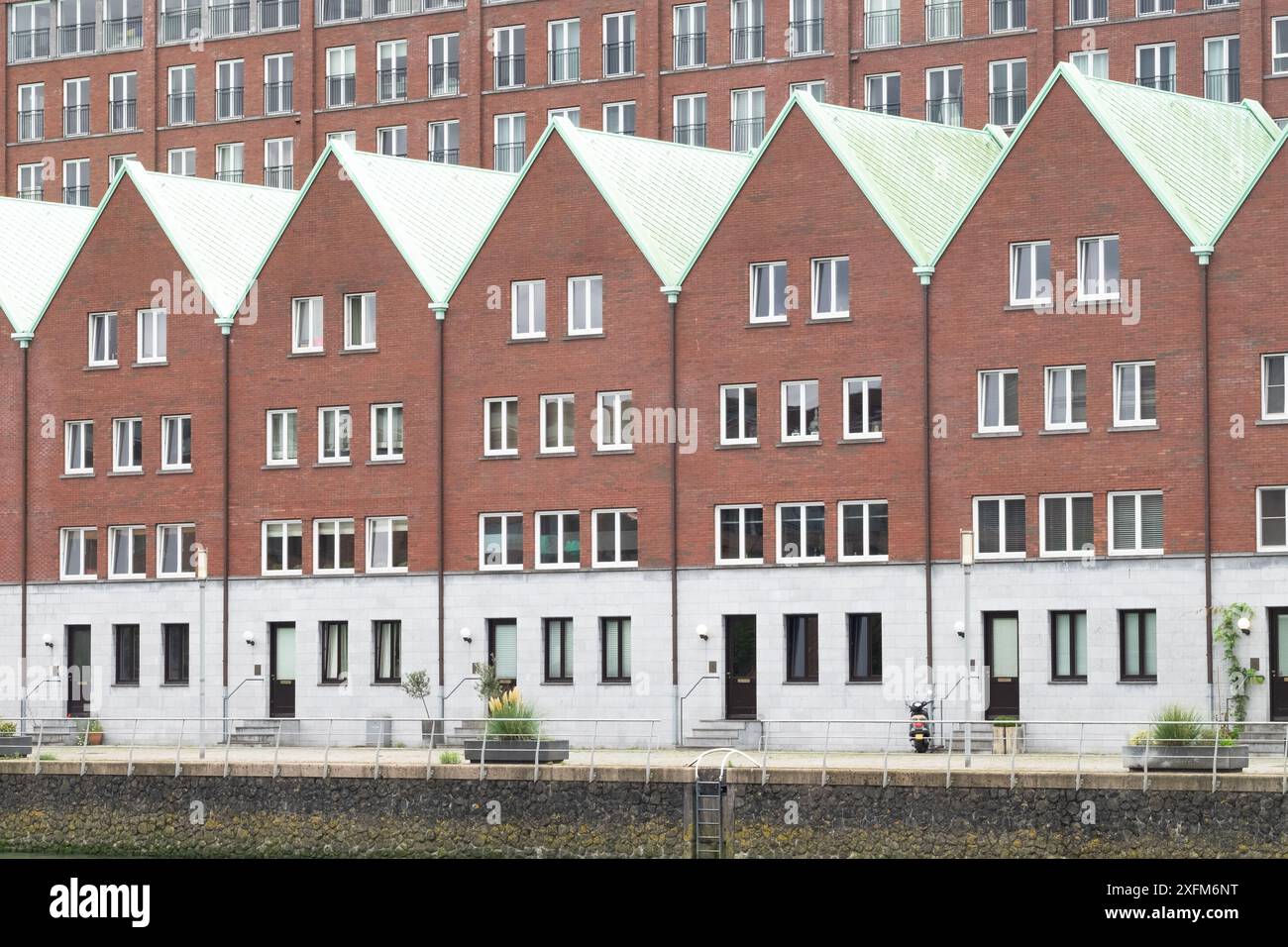 A row of brick buildings with a green roof. The buildings are tall and ...