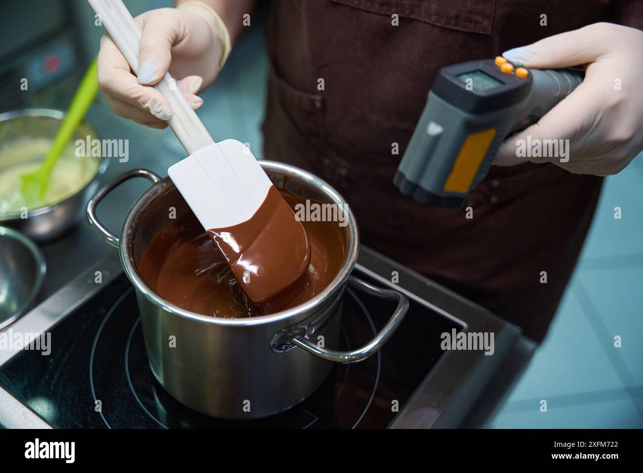 Woman holding kitchen thermometer and checking temperature of melted ...