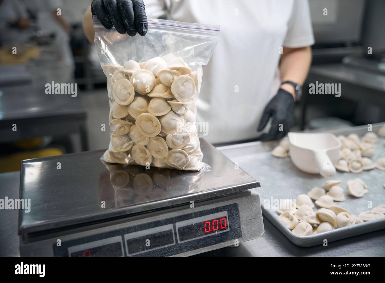 Workshop worker weighs a package of frozen dumplings on scale Stock ...