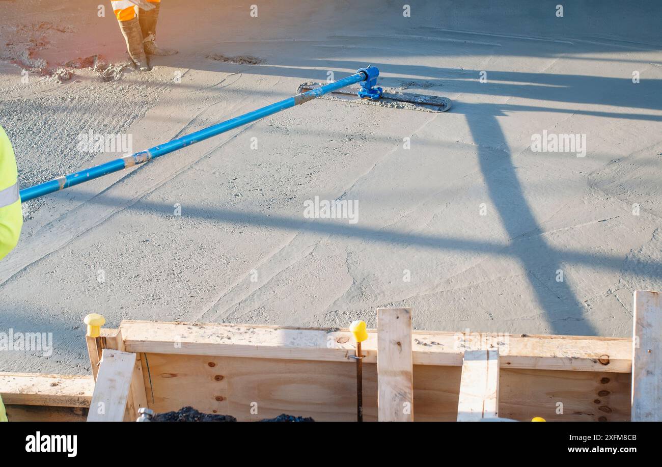 Builder using a steel pan and trowel to spread, level and smooth the ...