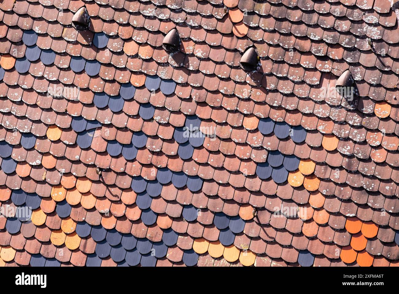 A roof with a pattern of orange and blue tiles. The roof is slanted and ...
