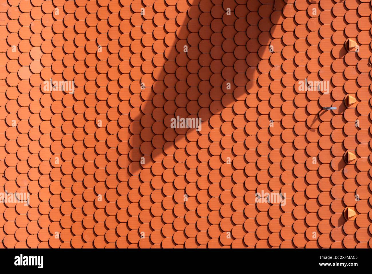 A red roof with a shadow of a knife on it. The shadow is dark and ...