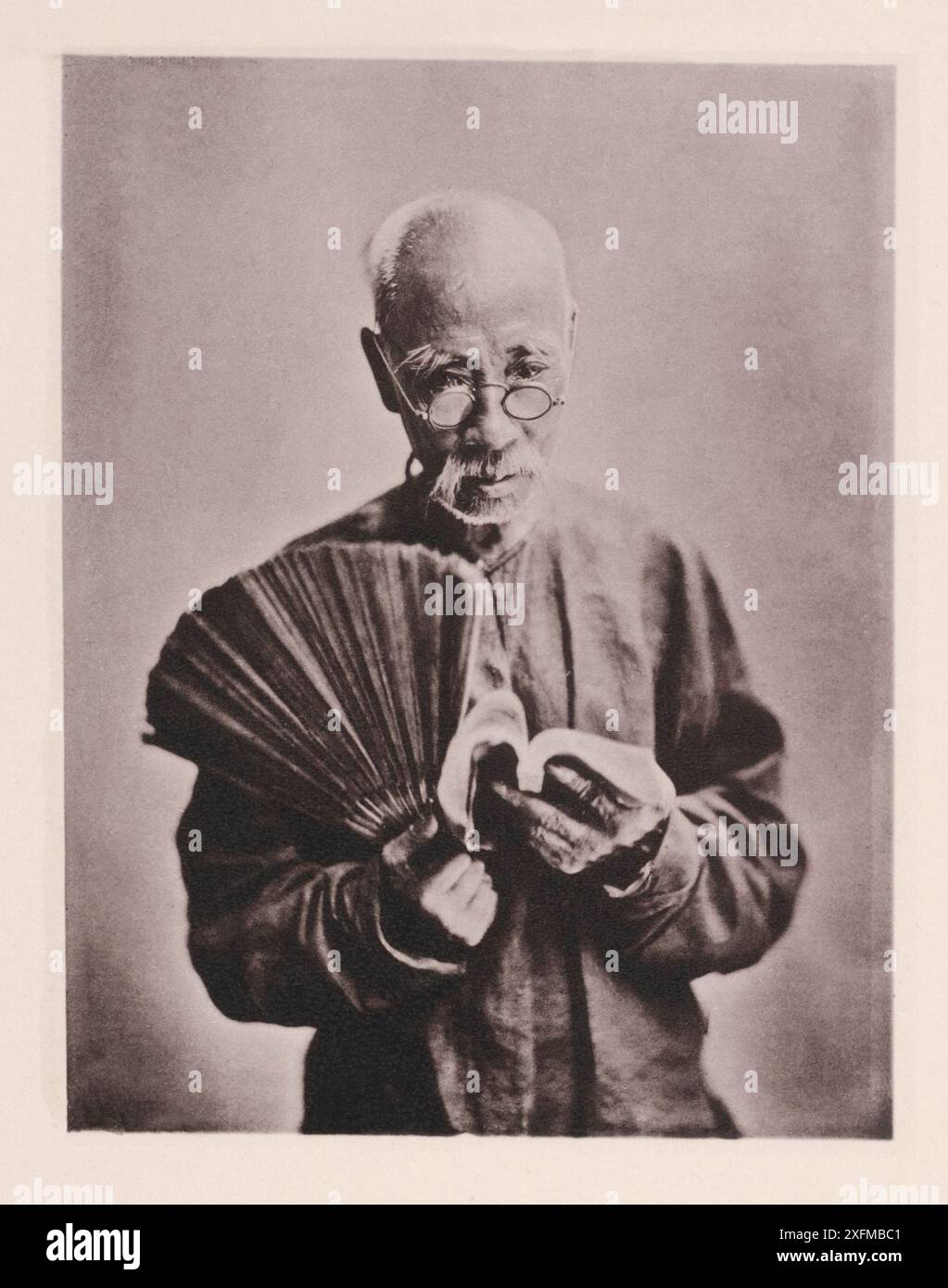 Vintage photo of an old Chinese man with a fan and in traditional dress ...
