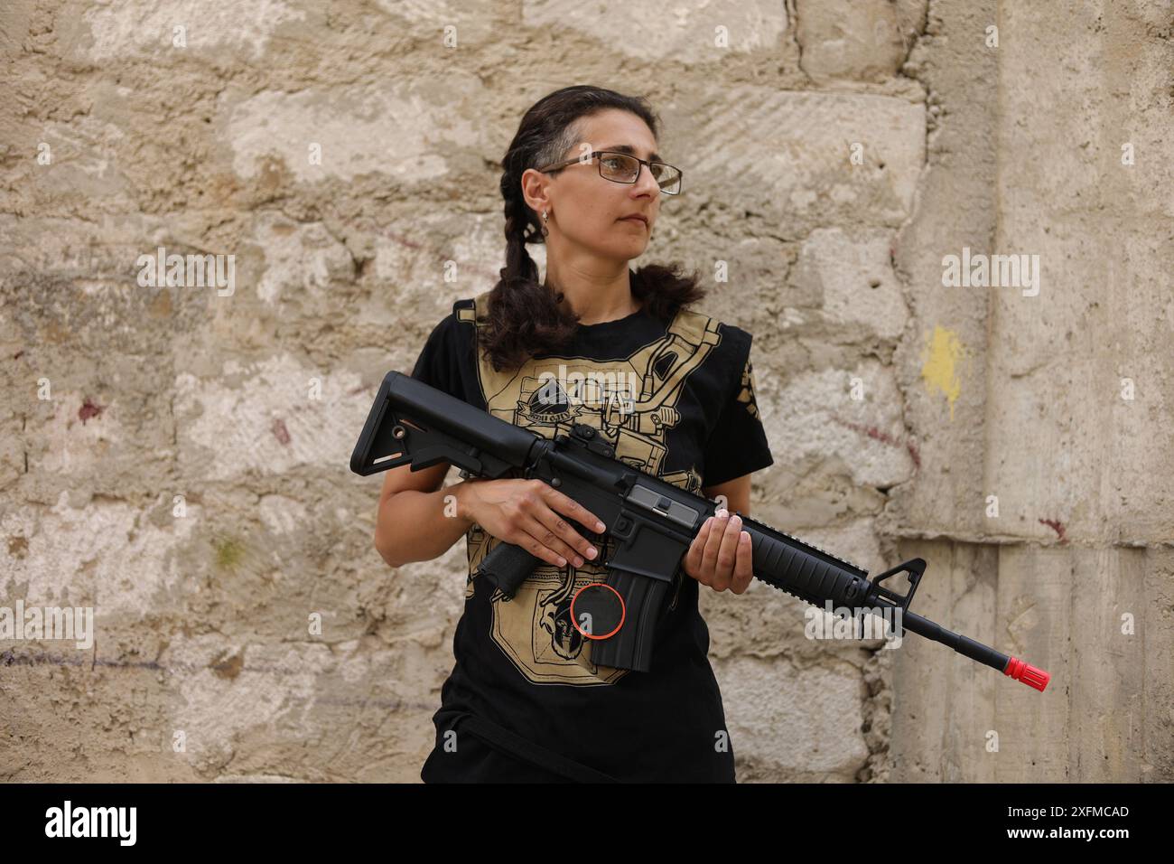 woman with long hair against the background of a wall with an airsoft ...