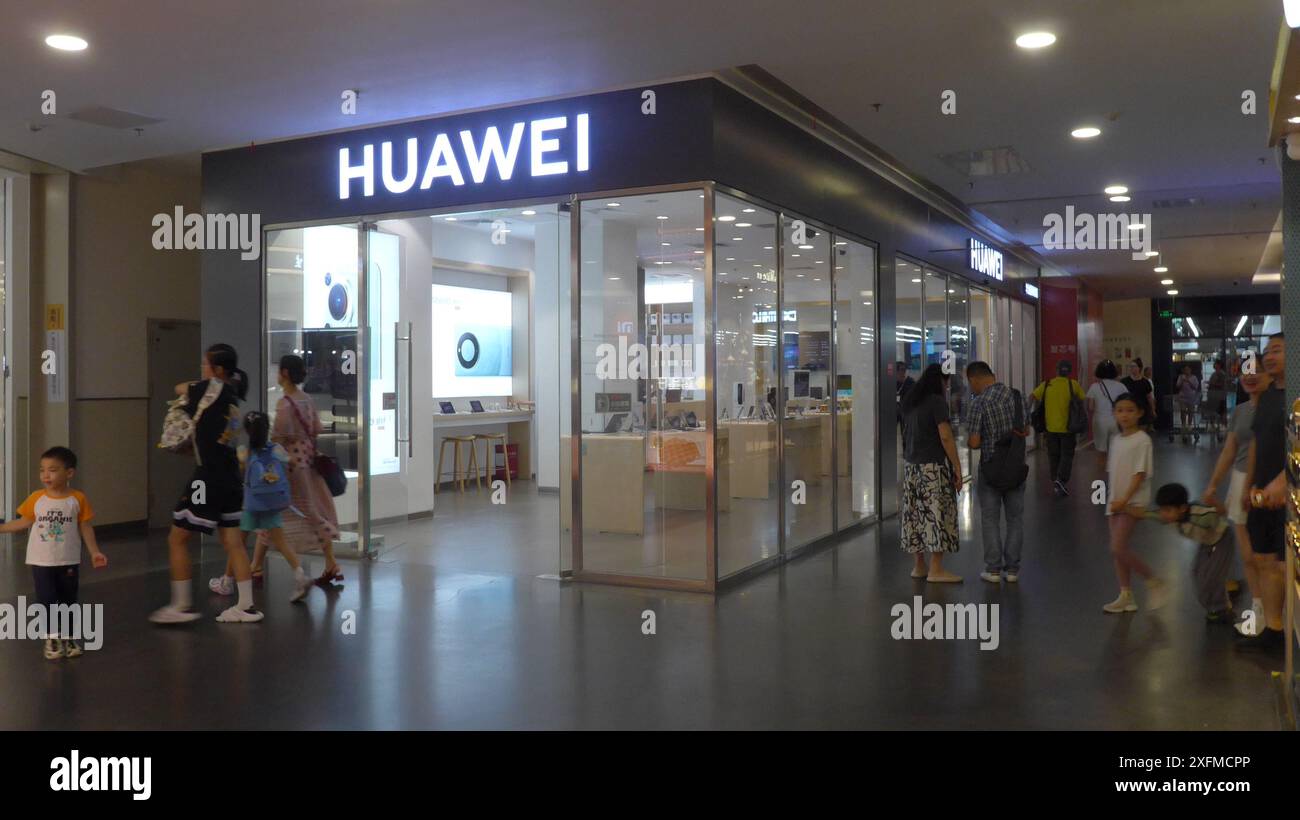 Pedestrians walk past the Chinese multinational digital communications ...