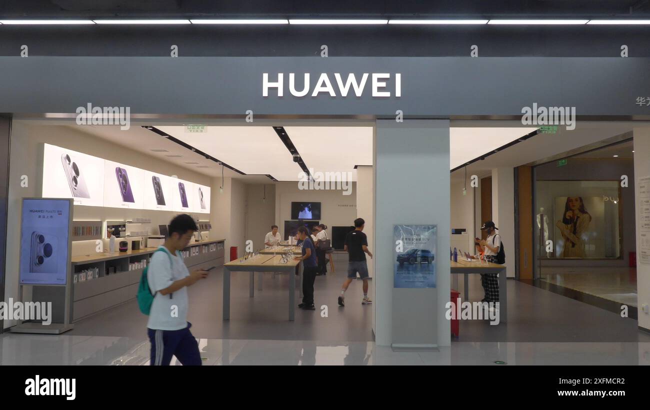 Pedestrian walks past the Chinese multinational digital communications ...