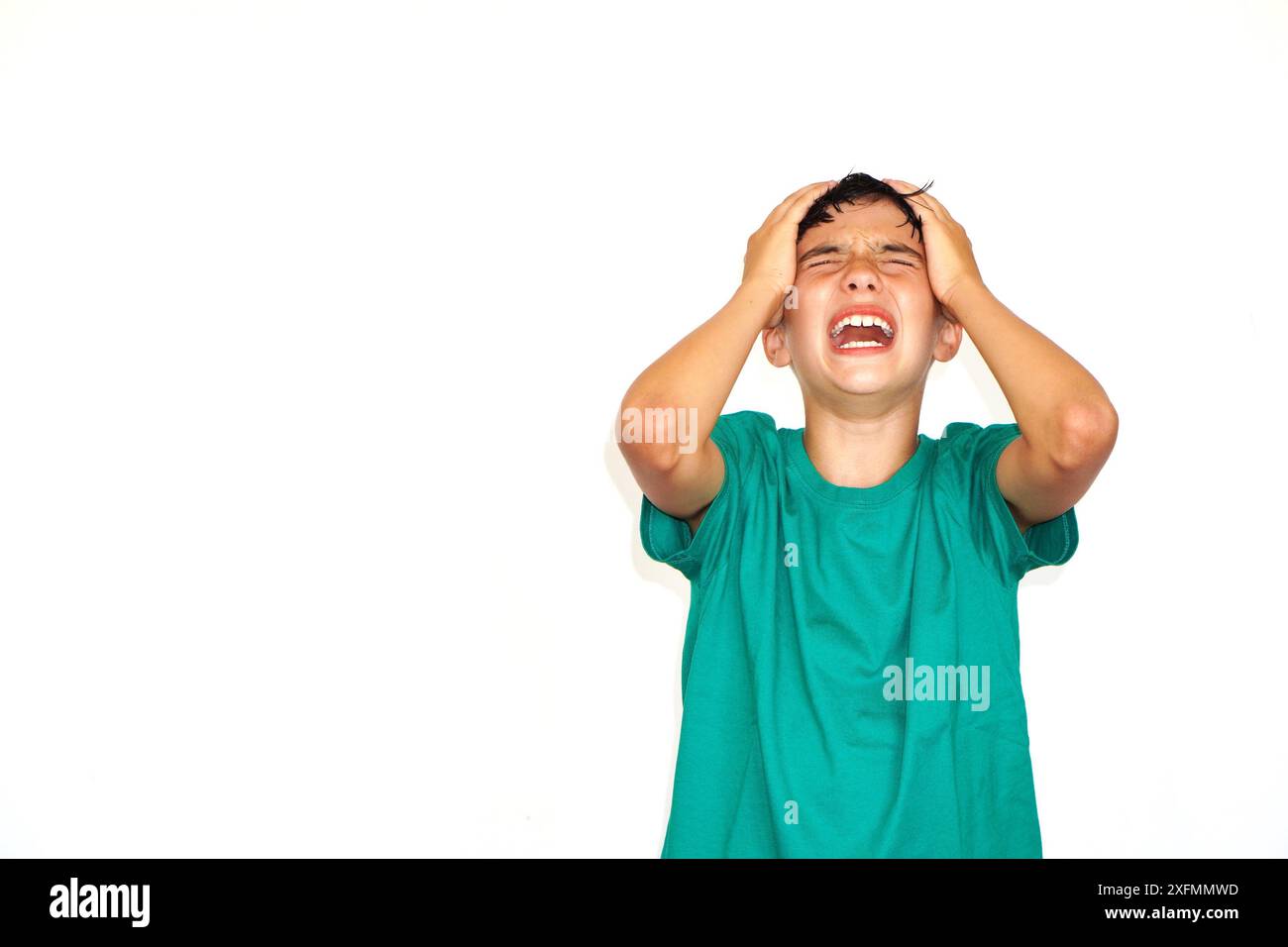 preteen boy with freckles holding his hands to his head with a pained ...