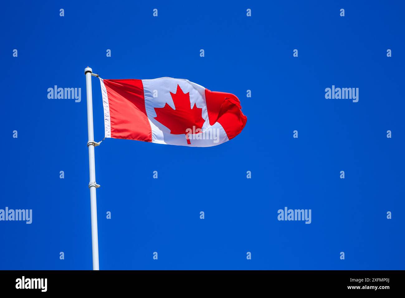 A red and white Canadian flag against a clear blue sky background Stock ...