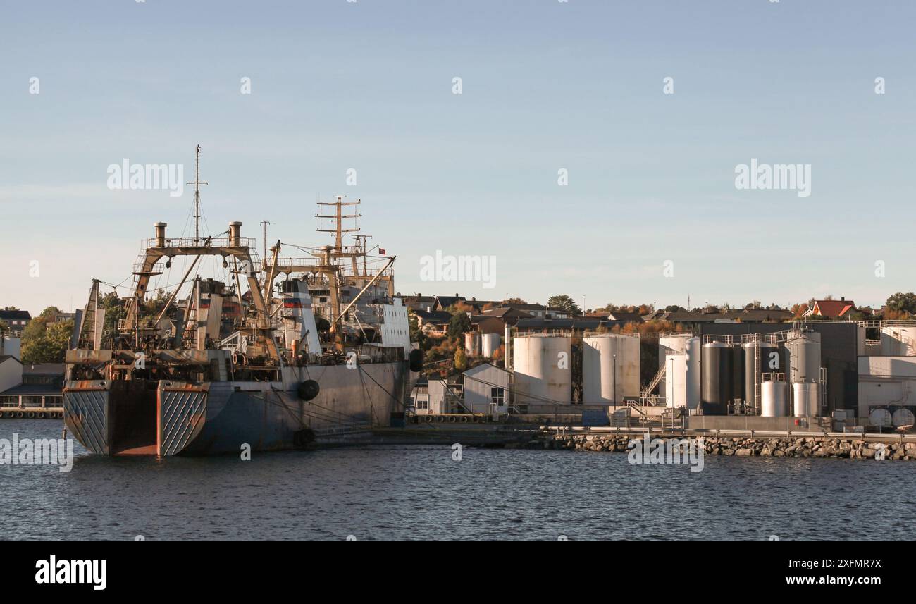 Kristiansund port view, trawler ship is moored in front of tanks on a ...