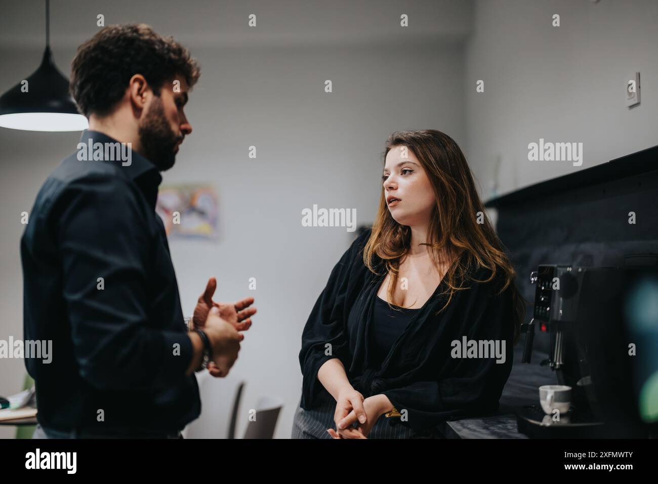 Colleagues in conversation during a coffee break in office kitchen ...