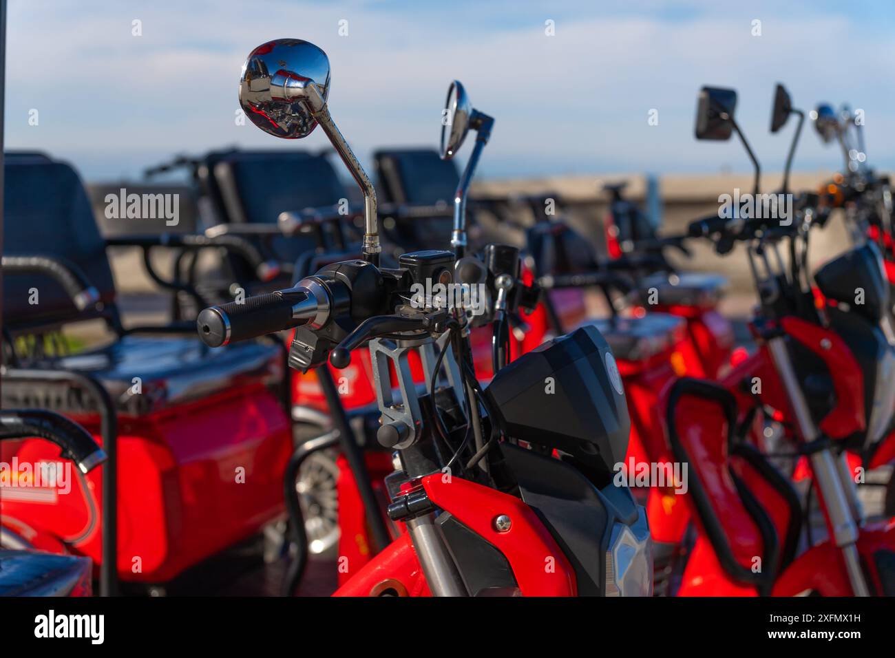 Close-up of red three-wheeled electric scooters on a blue sky ...