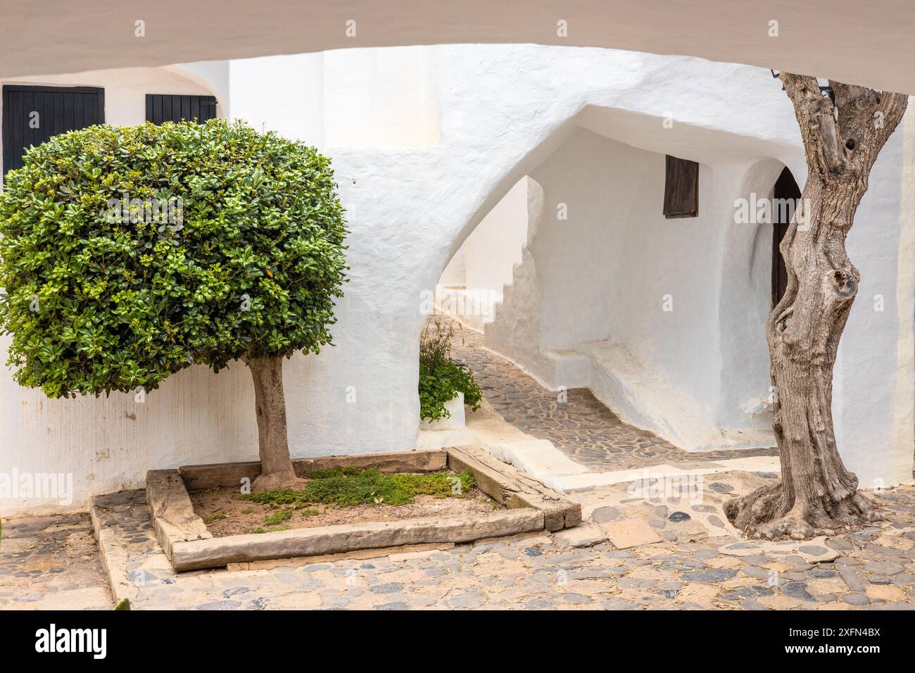 a narrow stone path between the white walls of the building, at the end ...