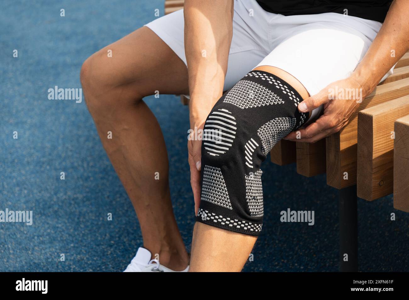 Man putting knee brace to support painful leg. Athlete bodybuilder leg ...