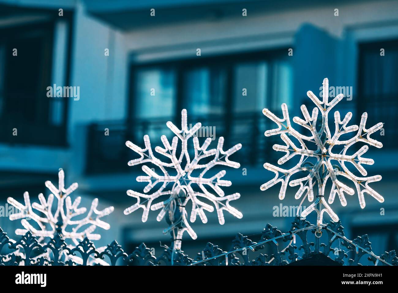 Decorative snowflakes are hanging on a fence. The snowflakes are made ...
