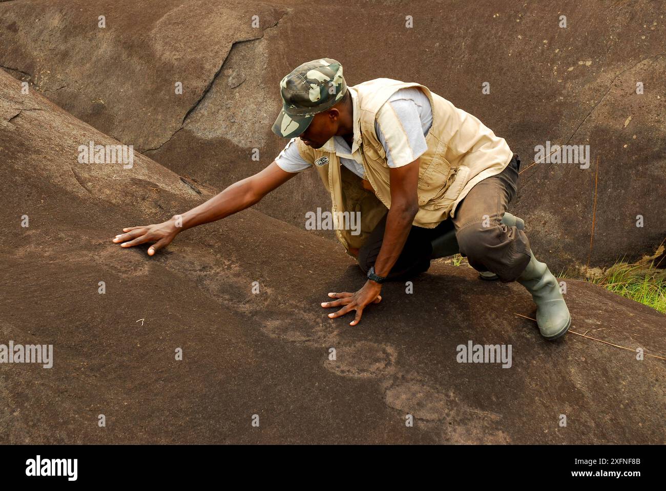 Man looking at petroglyphs, neolithic rock art. LopÃ© National Park ...