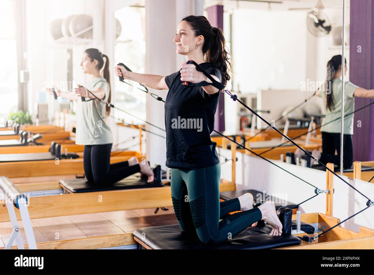 Two young, fit women training pilates on a reformer bed. Reformer ...