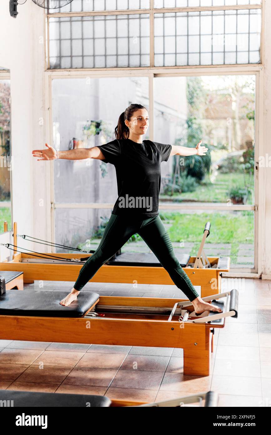 Young and fit woman training pilates on reformer bed. Reformer Pilates ...