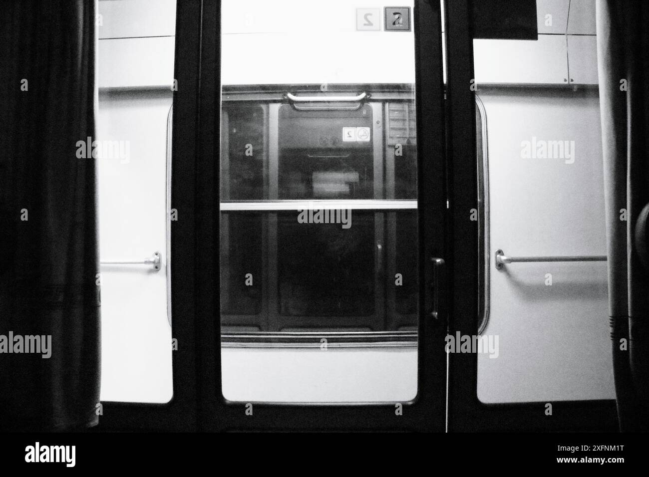 This black and white photograph captures the view from inside a train ...