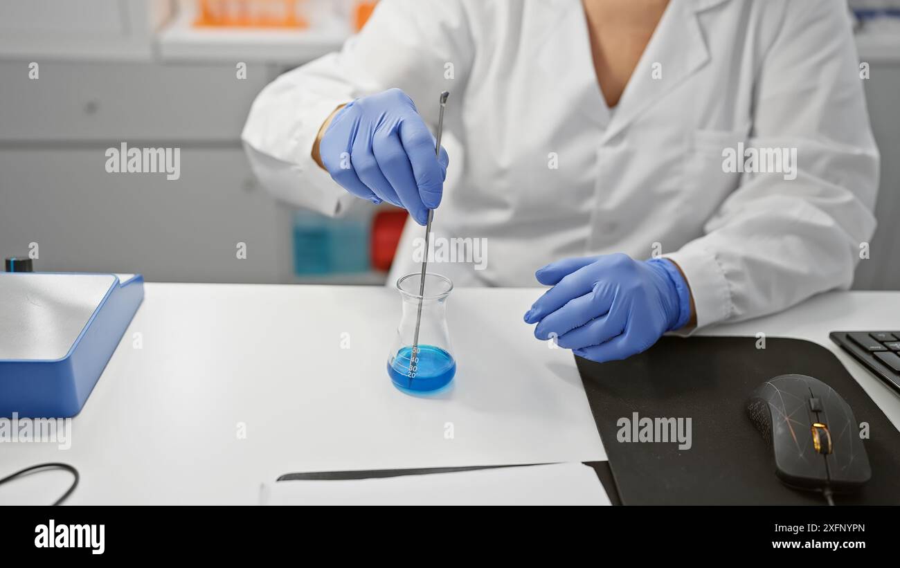 A woman scientist conducts an experiment using a pipette and beaker in ...