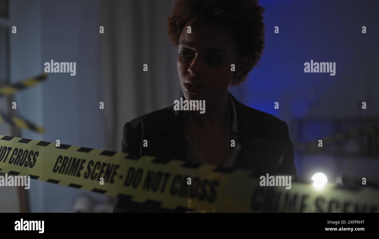 An african american woman in a dark room with crime scene tape across ...