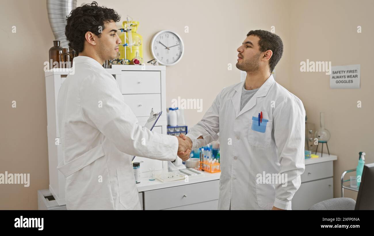 Two men in lab coats shaking hands in a laboratory with scientific ...