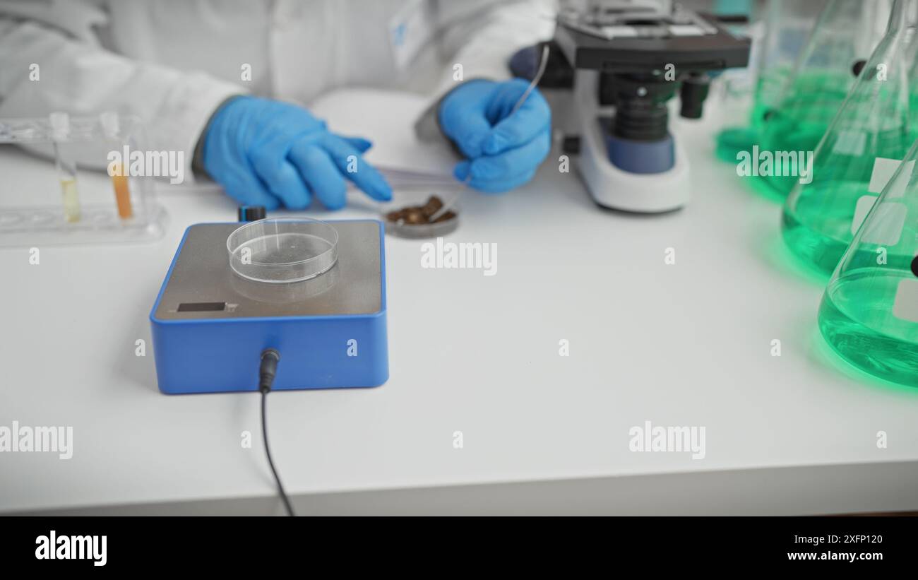 A scientist wearing gloves handling samples in a laboratory equipped ...