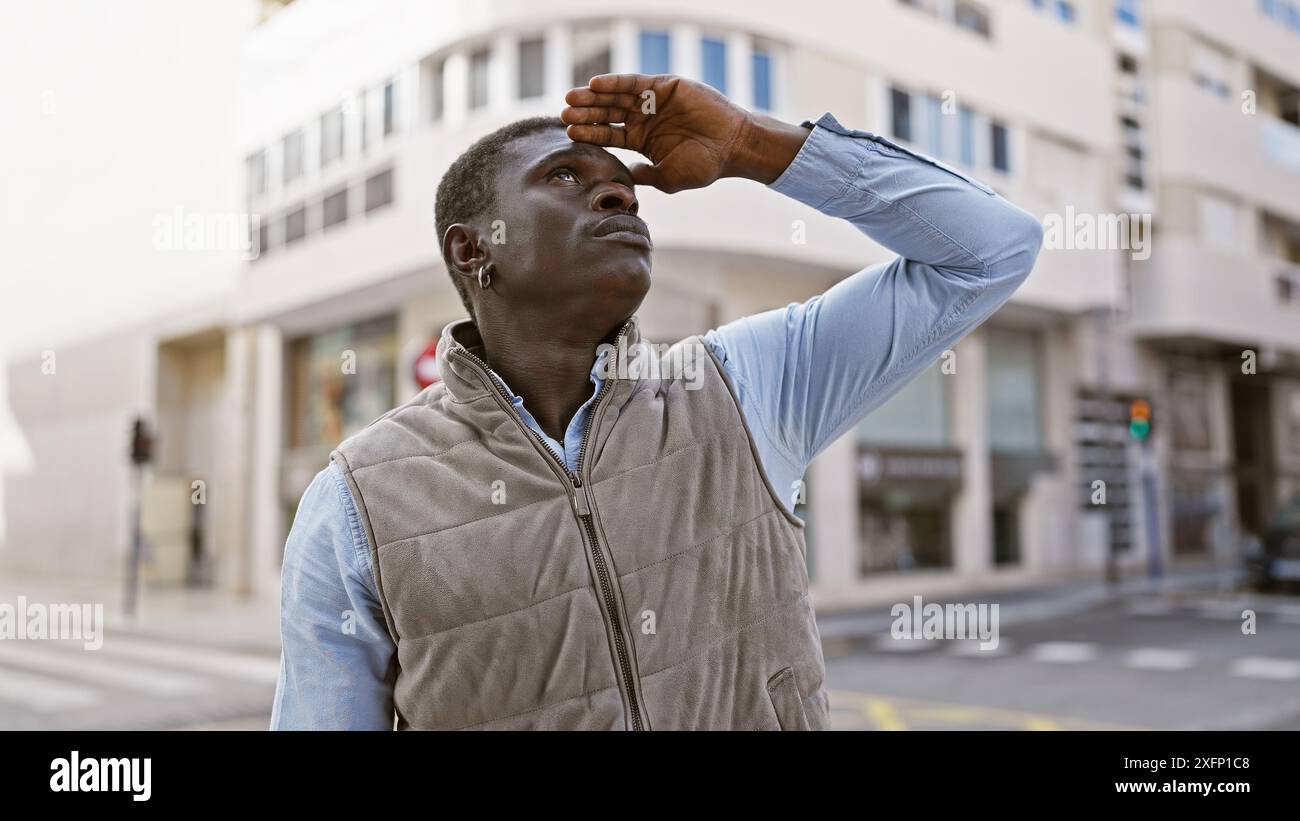African man shades eyes looking forward on urban street Stock Photo - Alamy