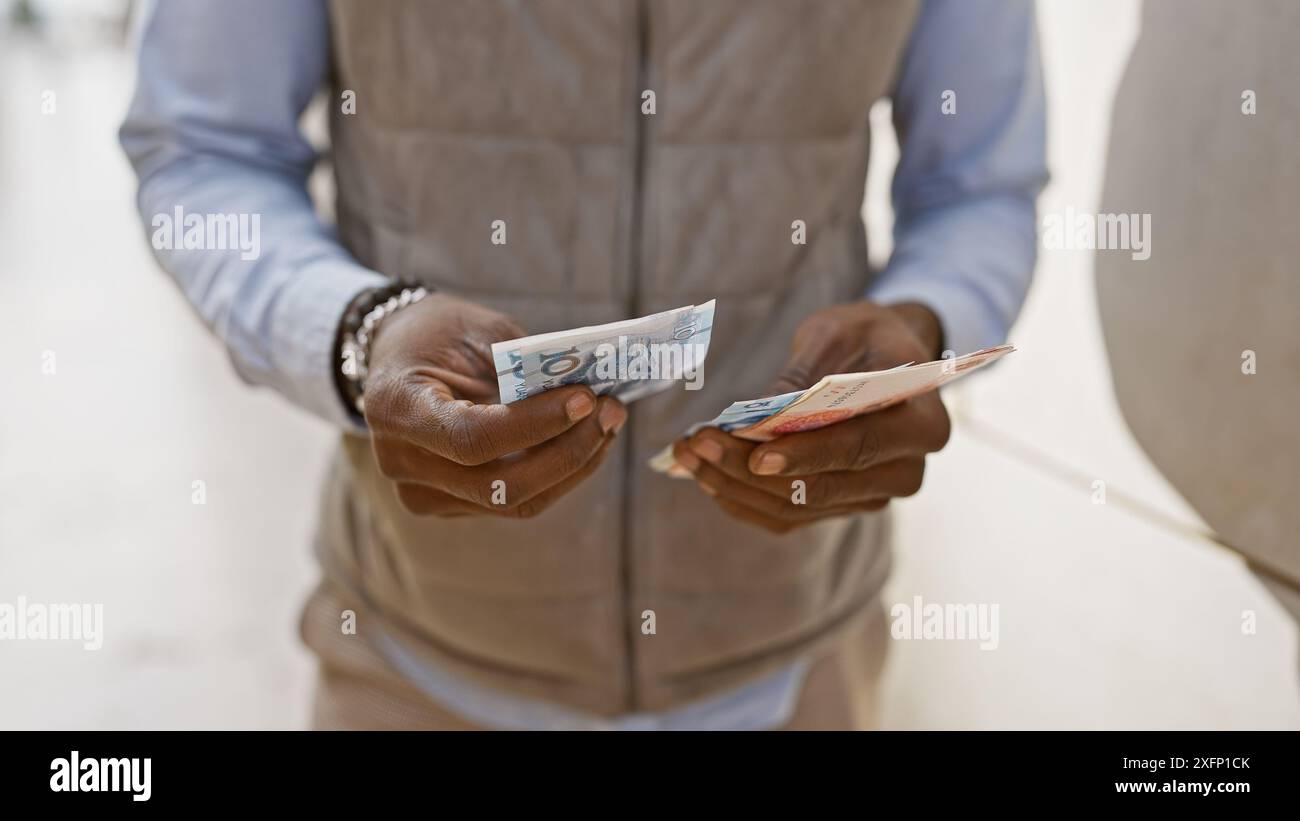African man counting chinese rmb currency on a sunny urban street ...