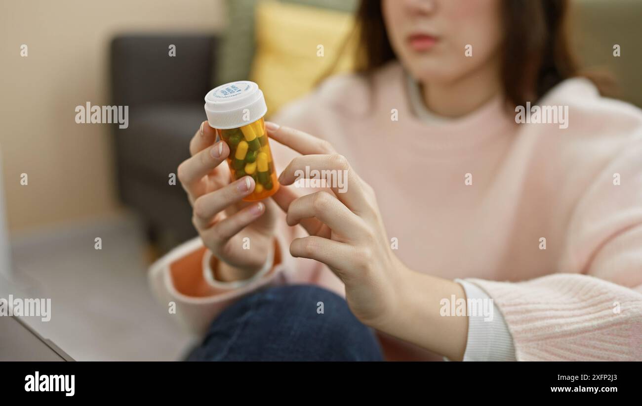 A focused young woman examines a prescription bottle in a cozy home ...