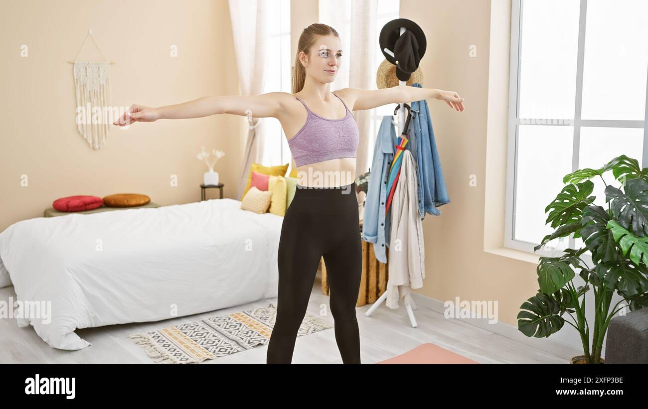 A young woman exercises in a tidy bedroom with plants, natural light ...