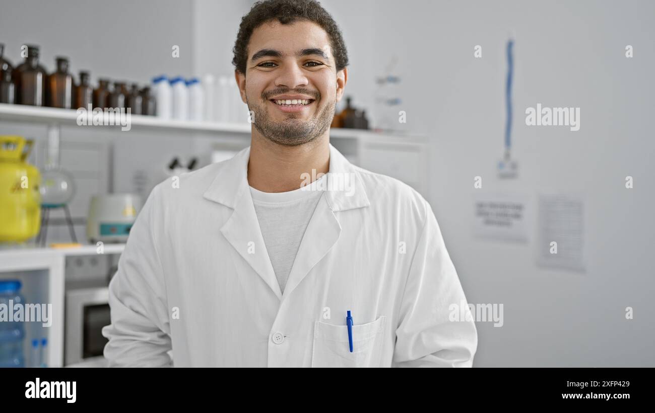 Smiling young man in white lab coat standing in a hospital laboratory ...