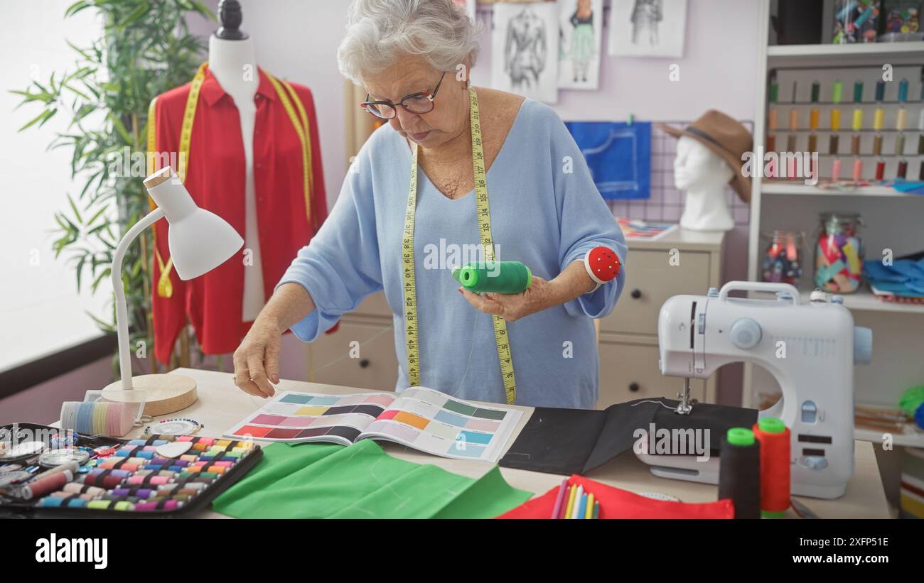 Senior woman sewing in tailor shop, selecting thread, surrounded by ...