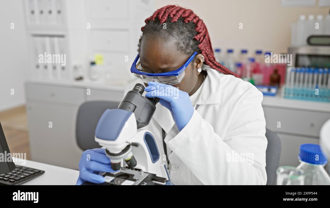 African american woman scientist with braids using microscope in ...
