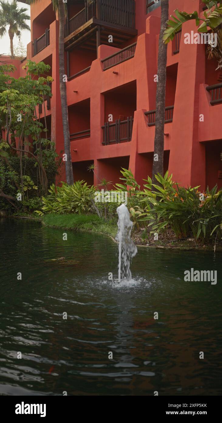 A scenic view featuring a terracotta resort building with a fountain ...