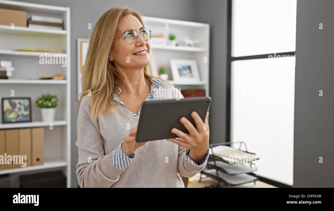 Blonde woman using tablet in modern office, conveying professionalism ...