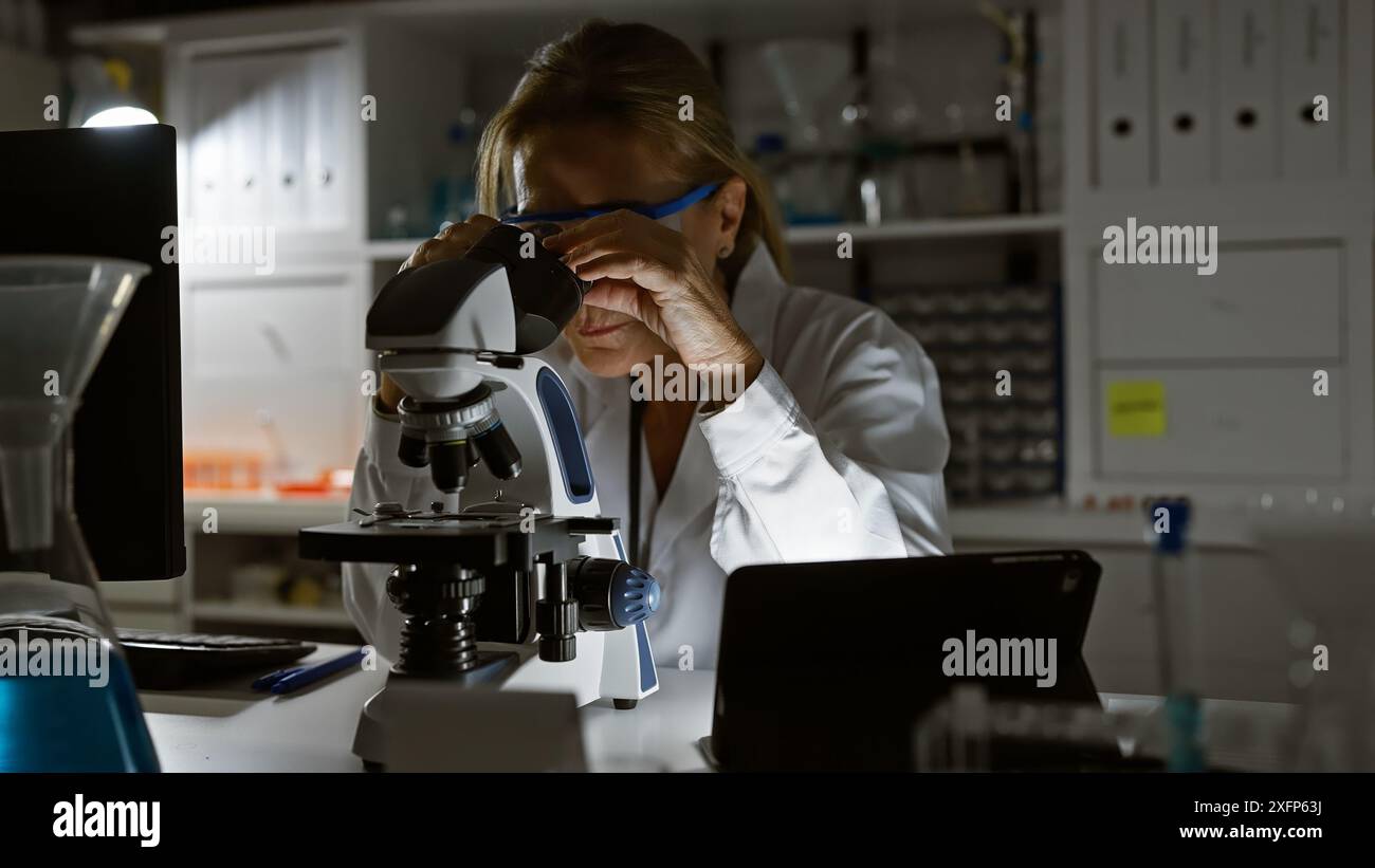 A mature woman scientist in a laboratory examines samples using a ...