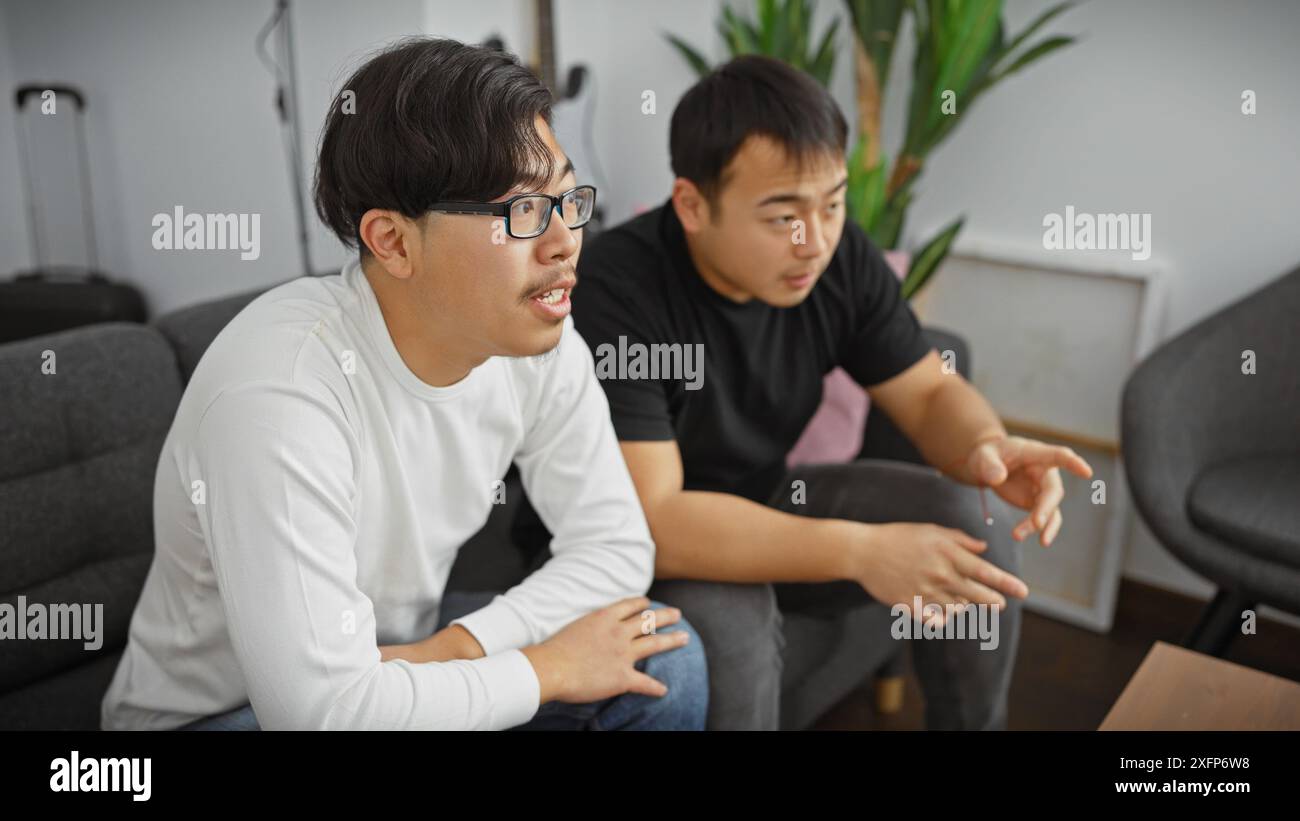 Two asian men engaged in an animated discussion while sitting in a ...