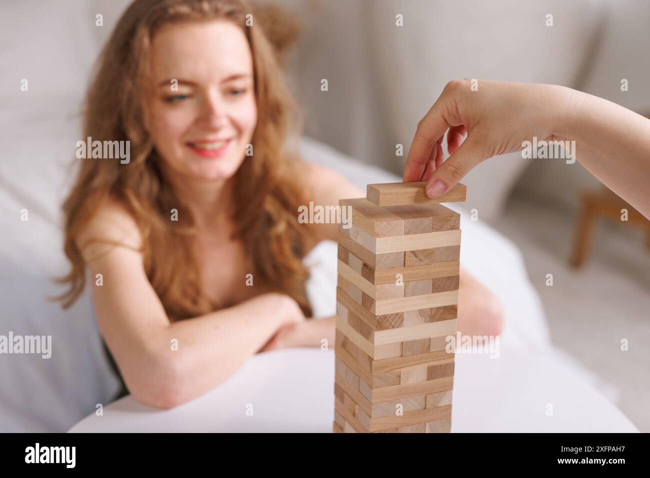 two women playing Jenga board game at home, excitement and relaxation ...