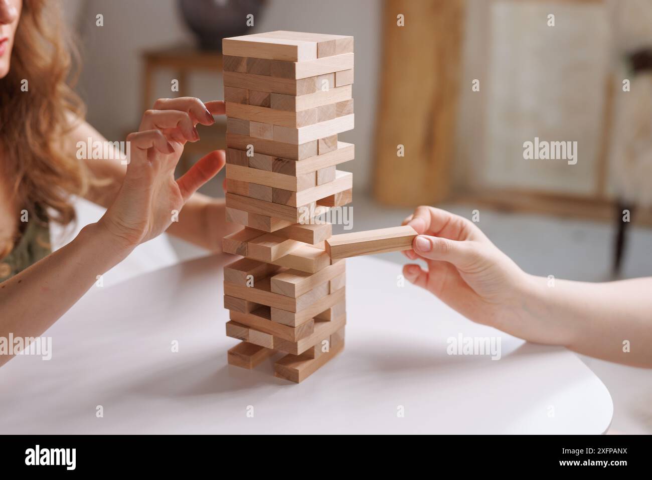 two women playing Jenga board game at home, excitement and relaxation ...